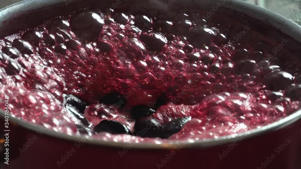 Cooking delicious red fruit jam, mixing and kneading. Close up ...