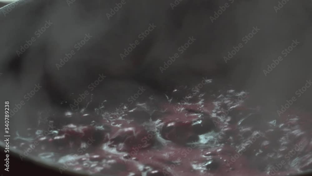 Cooking delicious red fruit jam, mixing and kneading. Close up ...