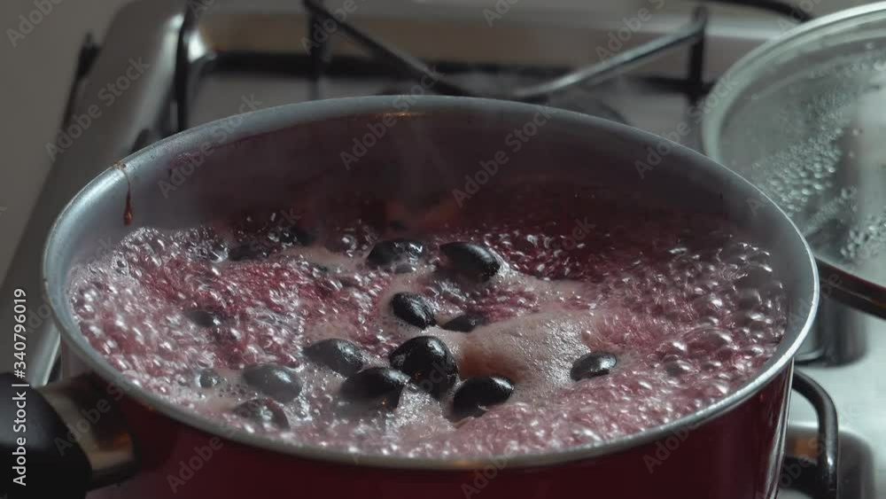 Cooking delicious red fruit jam, mixing and kneading. Close up ...