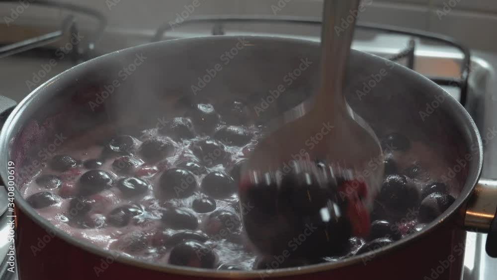 Cooking delicious red fruit jam, mixing and kneading. Close up ...
