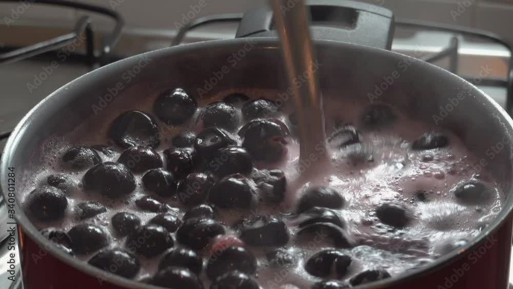 Cooking delicious red fruit jam, mixing and kneading. Close up ...