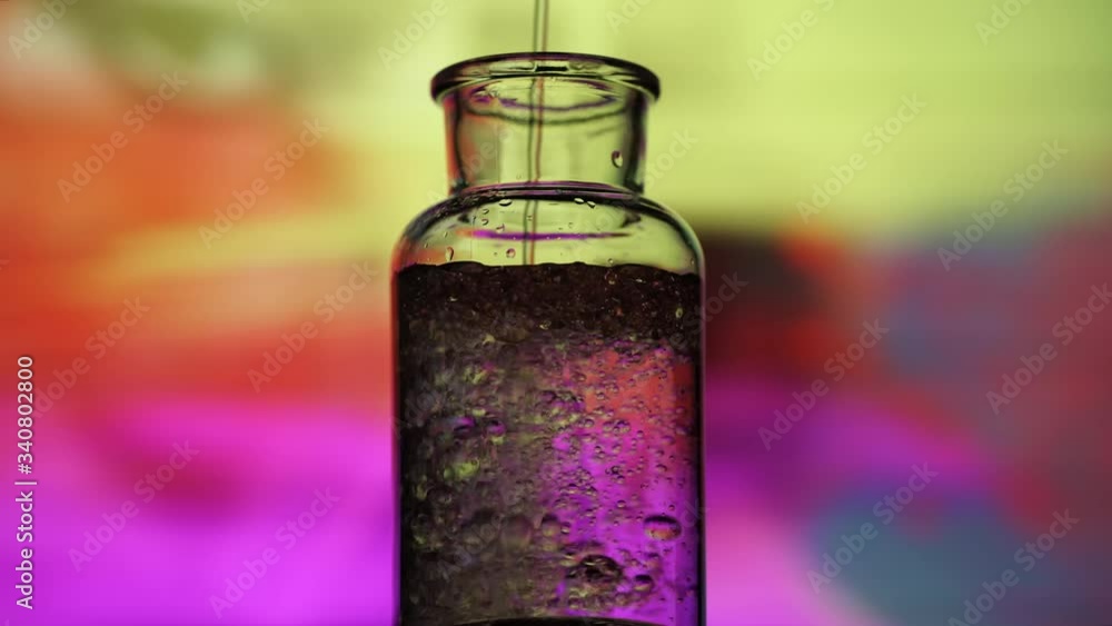 Mixing two liquid substances in chemistry lab jar on neon colored ...