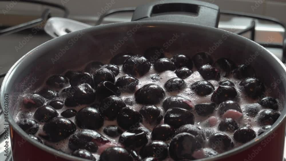 Cooking delicious red fruit jam, mixing and kneading. Close up ...