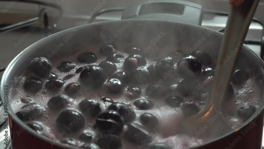 Cooking delicious red fruit jam, mixing and kneading. Close up ...