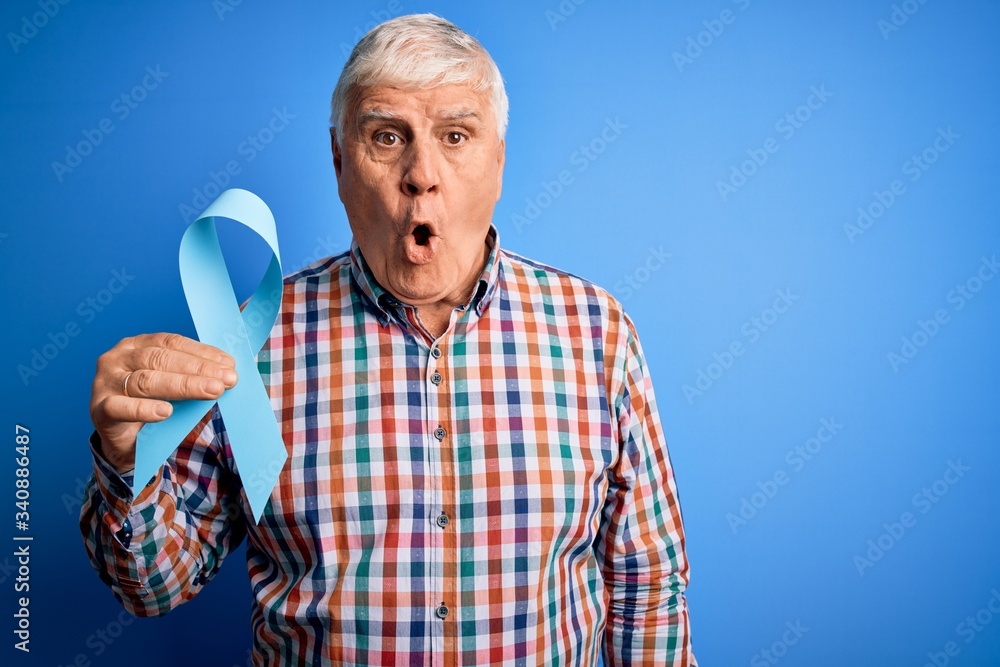 Senior handsome hoary man holding blue cancer ribbon symbol over ...