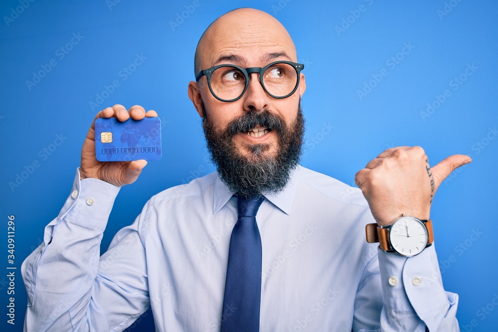 Handsome bald business man with beard holding credit card over isolated ...