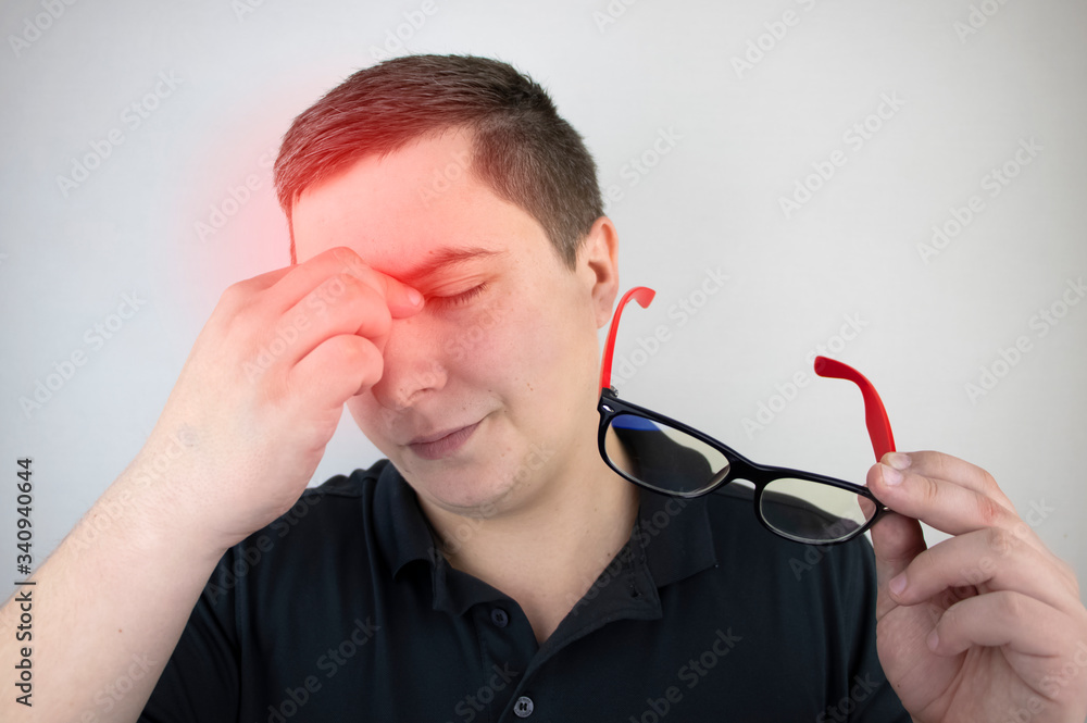A man rubs his tired eyes with his hands on a white background. The ...