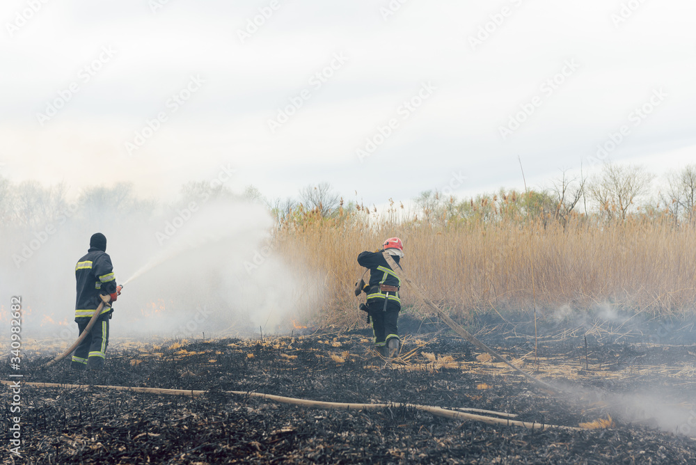 Firefighters battle a wildfire. firefighters spray water to wildfire ...