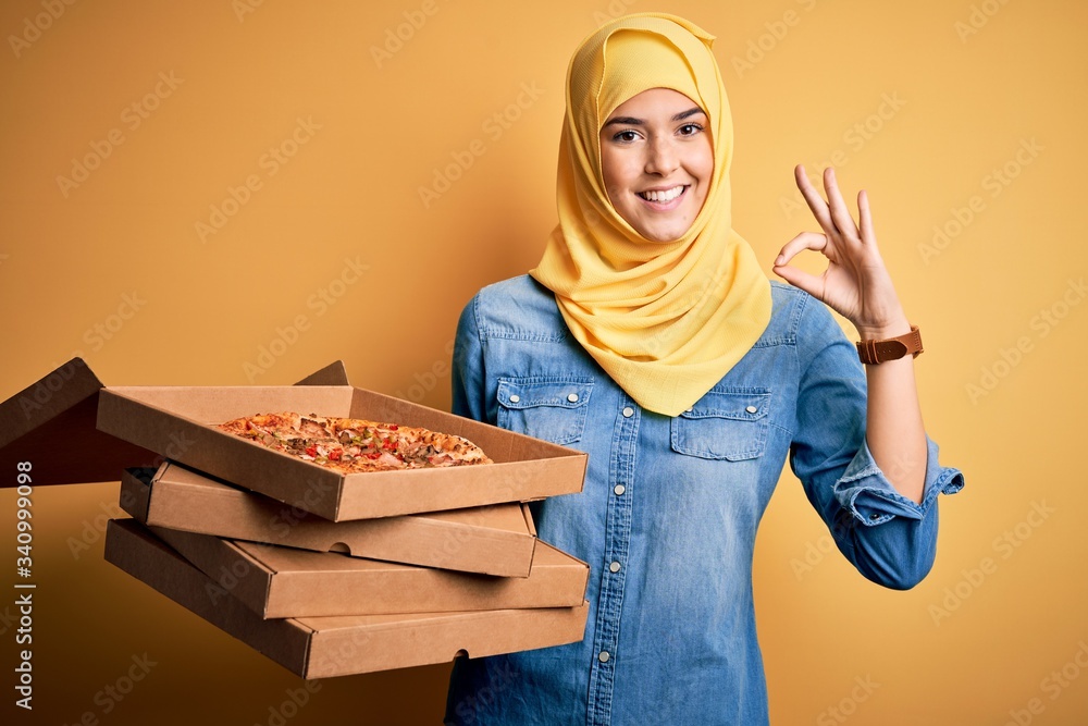 Young girl wearing muslim hijab holding boxes with Italian pizza over ...