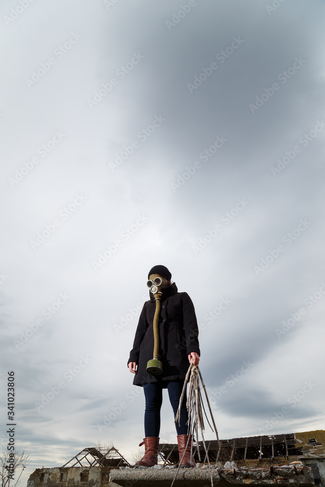 Human in gas mask standing among ruins and dramatic sky background ...