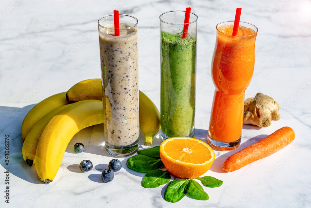 3 different kind of smoothies with ingredients on marble table ...