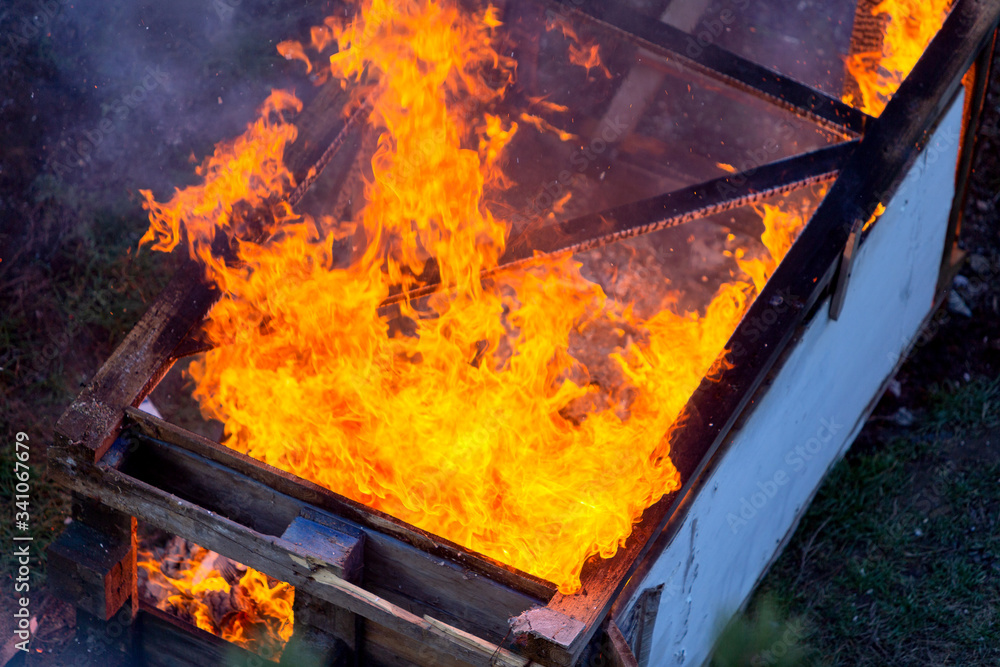 Fire coils over a burnt building. A pile of coals at the site of a ...
