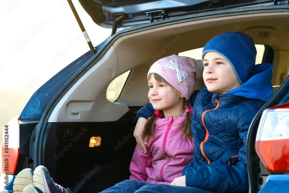 Two happy children boy and girl sitting together in a car trunk ...