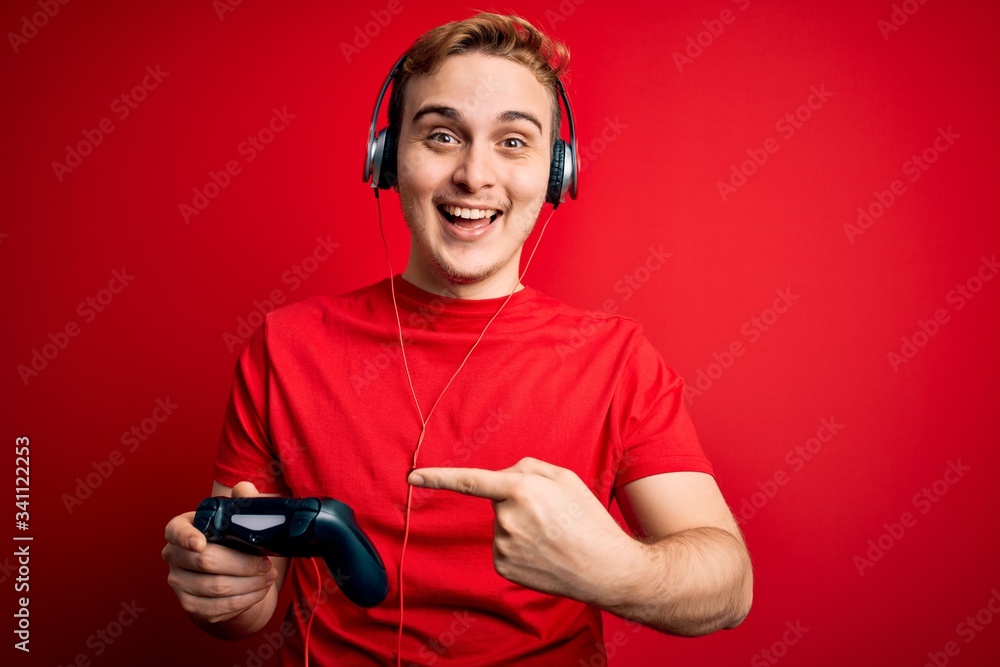 Young handsome redhead gamer man playing video game using headphones ...