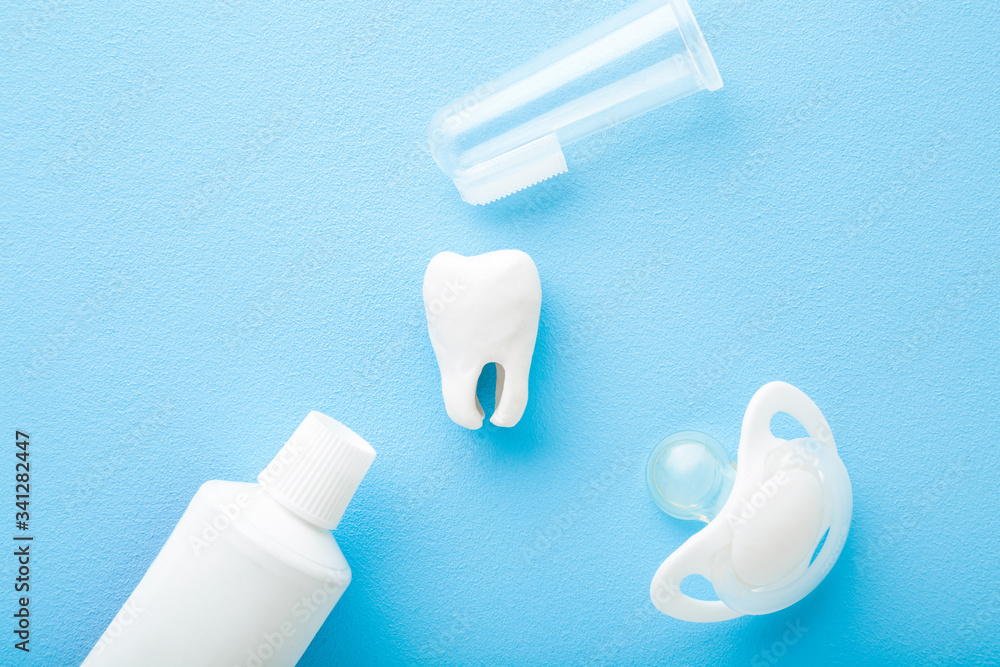 White tooth, tube of toothpaste, soother and transparent silicone ...