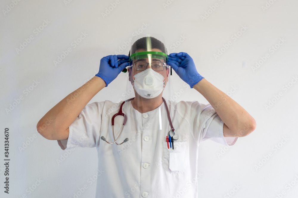 Male nurse putting on a face shield He is a young man. He wears gloves ...