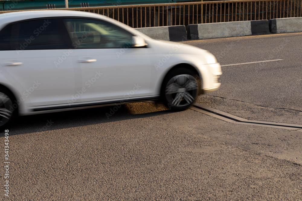 Metallic zigzag edge of drainage channel on asphalt. A blurry car over ...