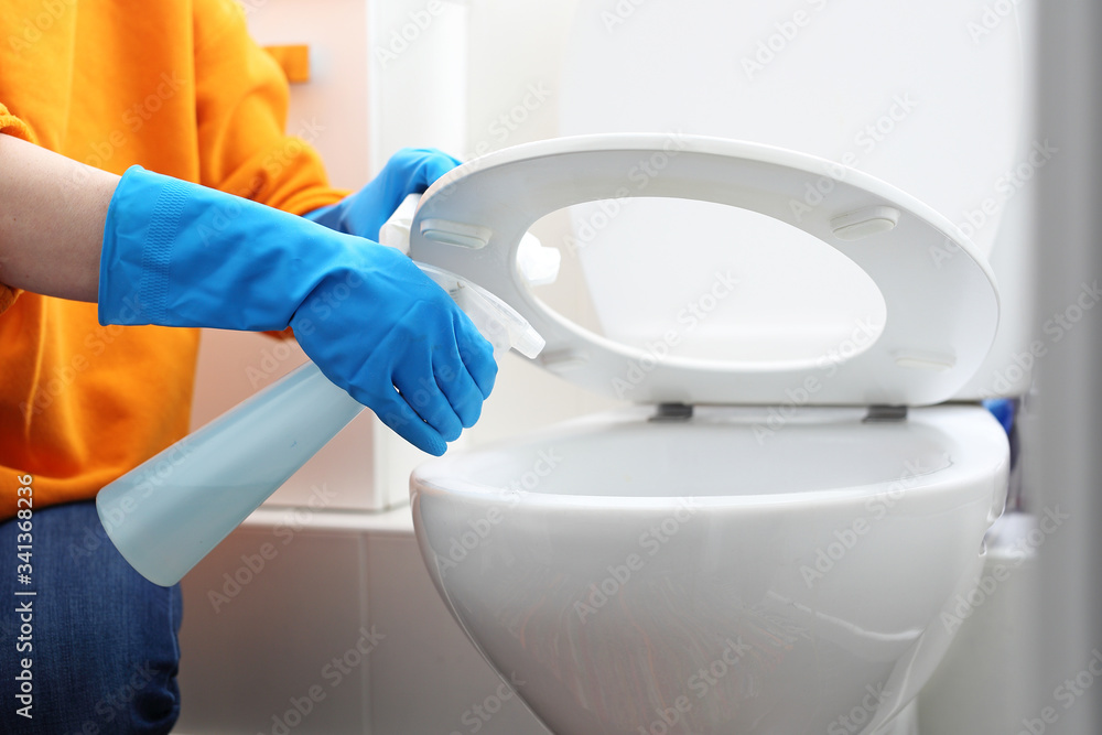Cleaning the toilet. A woman cleans the toilet with a disinfectant ...