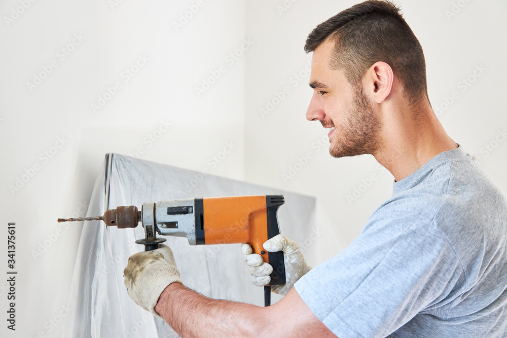 Man as a craftsman with drill on wall Stock Photo | Adobe Stock