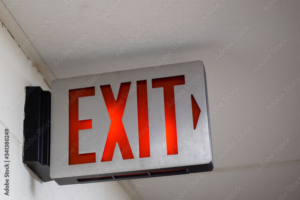 red emergency exit sign in the dark room. illuminated office exit sign ...