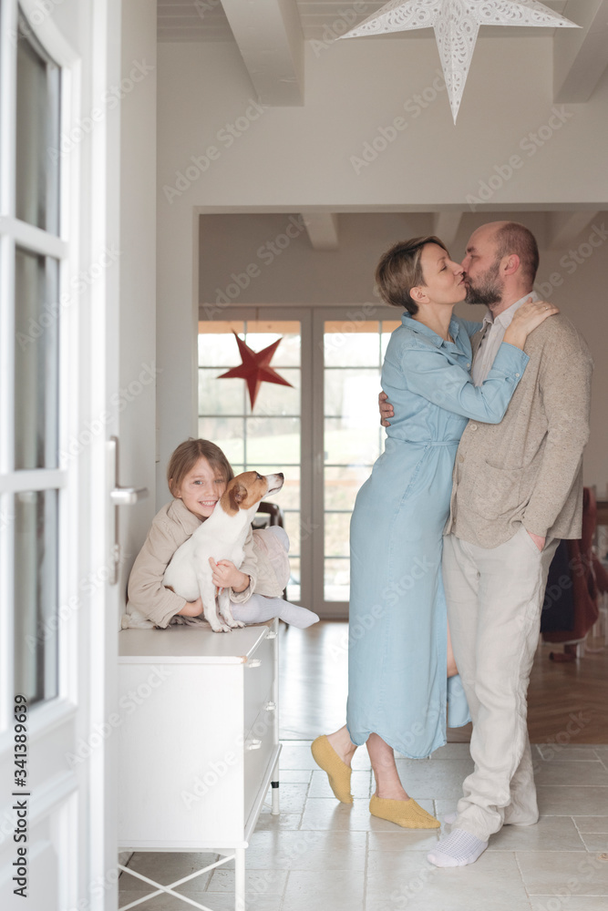 Lttle daughter hugging dog and her parents kissing in hallway Stock ...