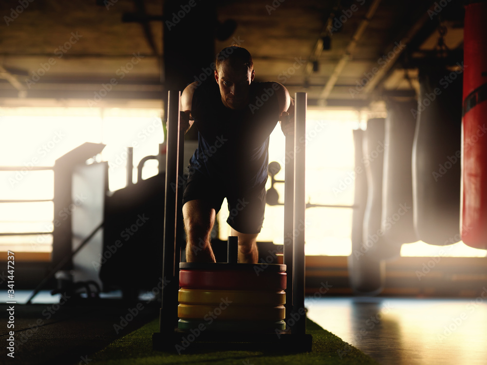 Full length backlit shot of athletic middle aged man pulling weight ...
