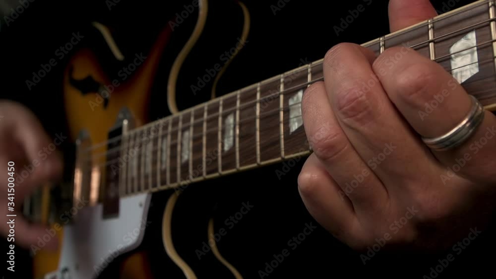 Extreme close up of a man's fingers forming chords on the neck and ...