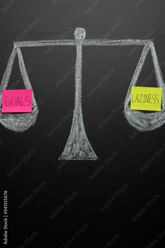 Scales drawn on a blackboard with the words goal and laziness. Concept ...