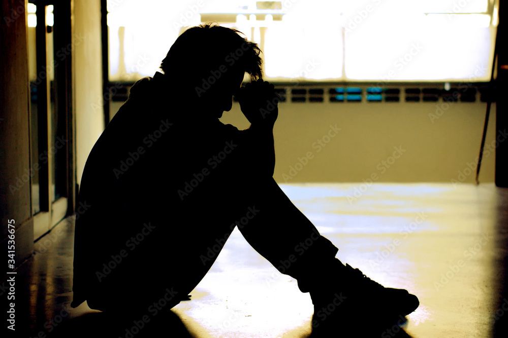 sad silhouette of man in depression sitting with his head down,dramatic ...