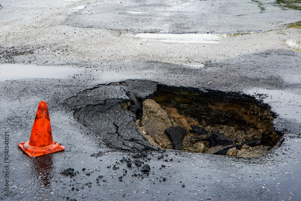 huge pit hole on the road, failure in the asphalt, marked with an ...