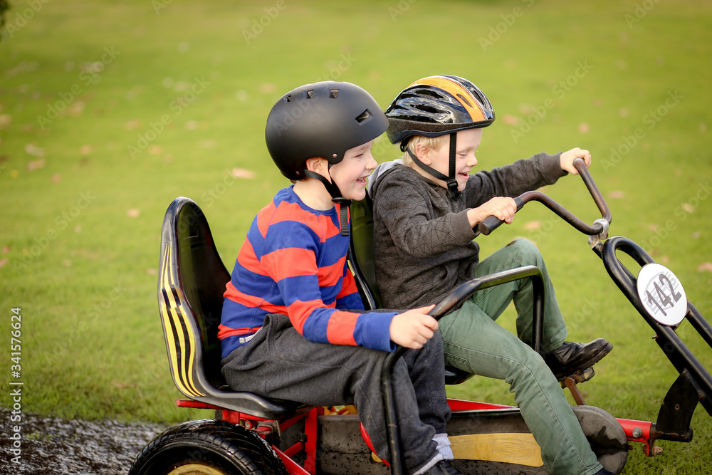 Happy little boys riding two person pedal cart at caravan park in ...