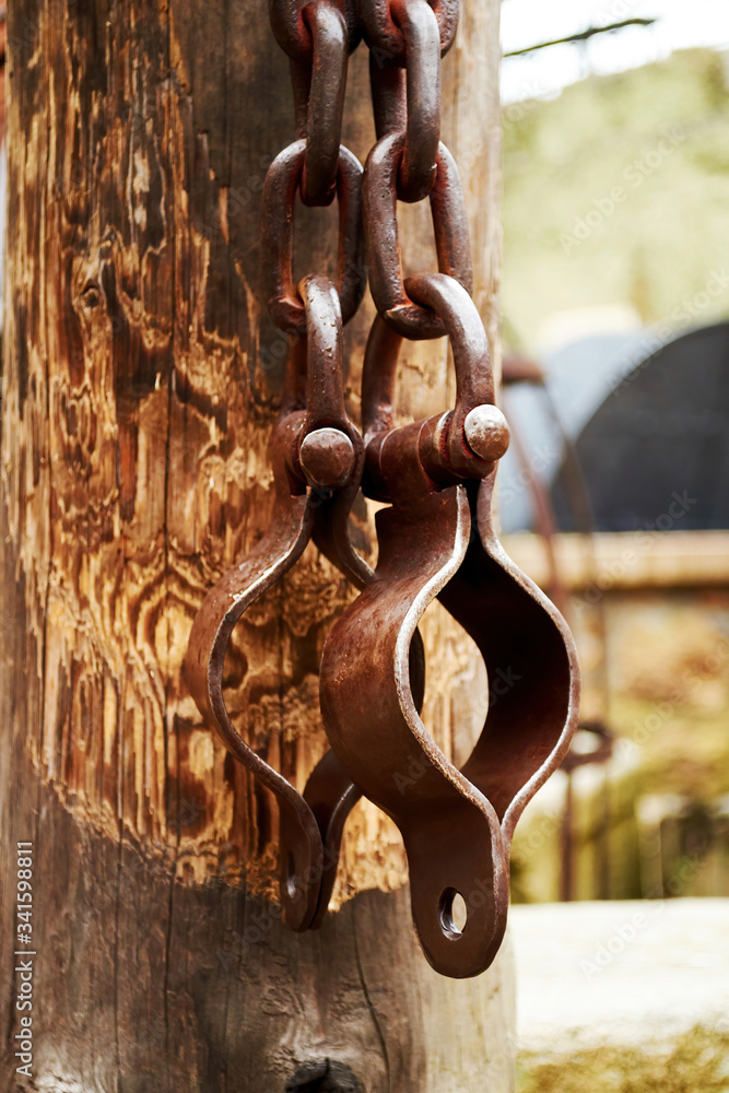 Medieval prisoner handcuffs hanged on a wooden pillar of an old ...