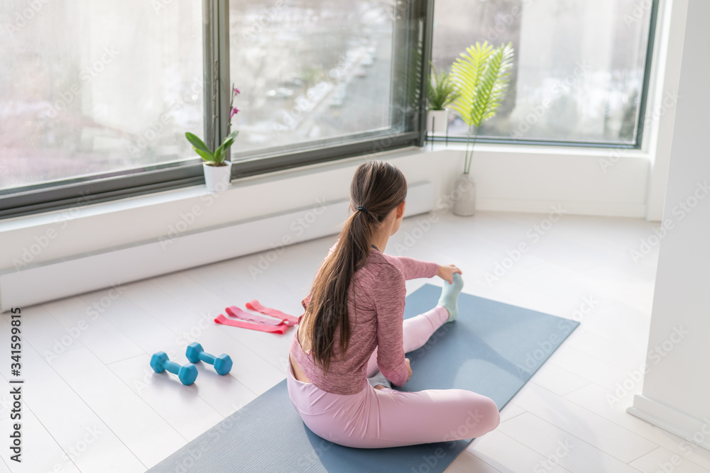 Woman exercising at home stretching legs before yoga training workout ...