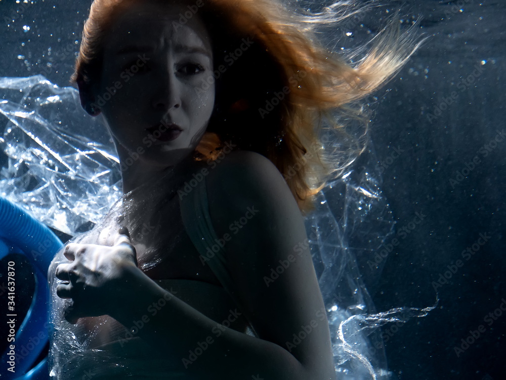 Woman swimming underwater among plastic trash. Girl drowning in sea ...