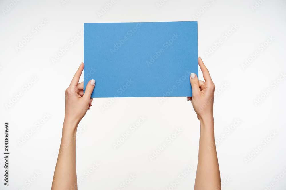 Well-groomed young female's hands keeping light blue piece of paper A4 ...