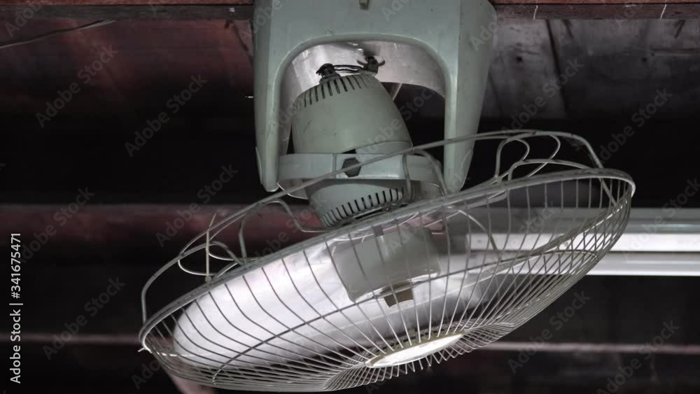 An electric fan is circling on the wooden ceiling. The ventilator ...