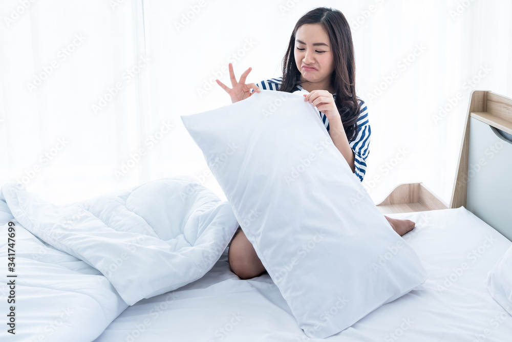 An Asian woman sniffing a white pillow, which smelled smelly and damp ...
