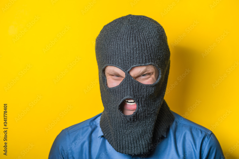 man close up thief in a mask and a blue shirt on a yellow background ...