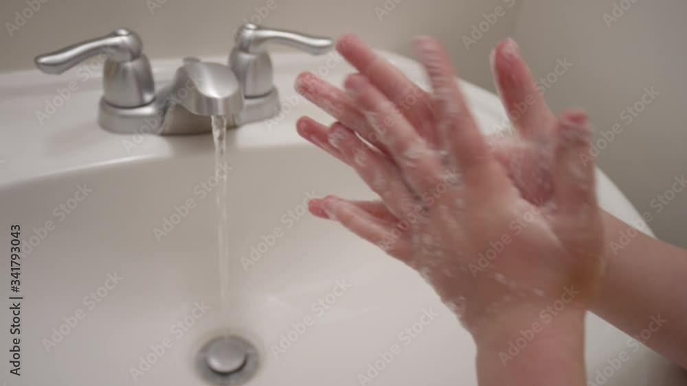 Close up of a sink and hands rinsing off soap under water in slow ...