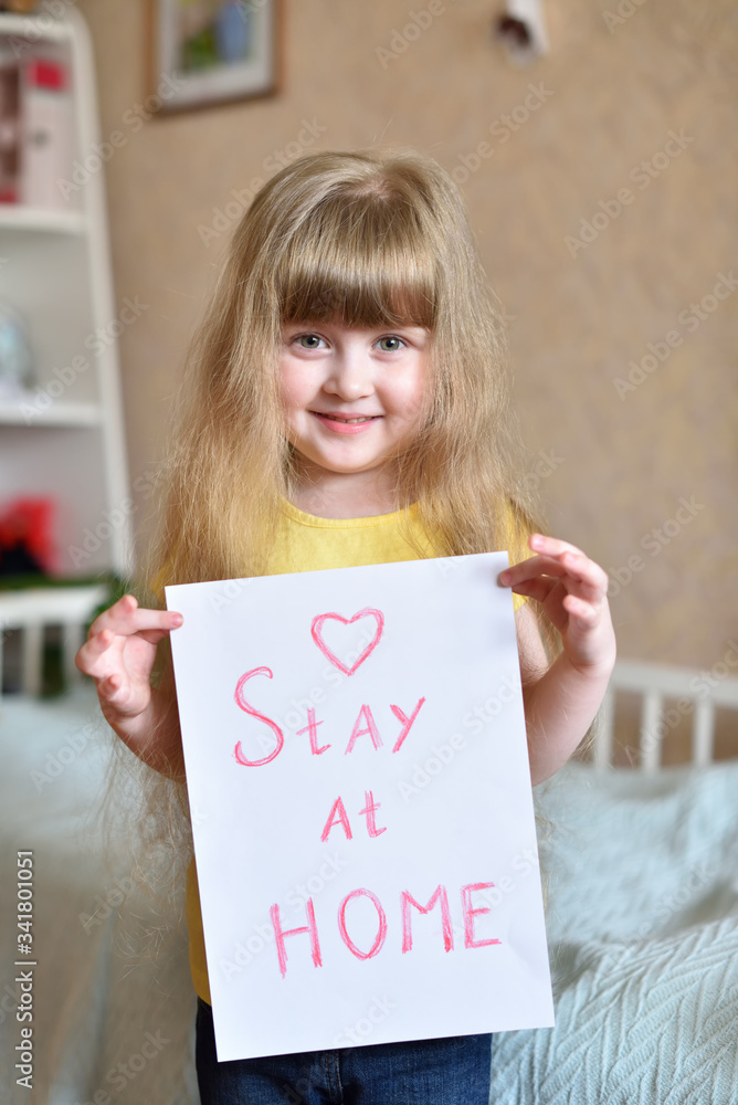 Stay at home - an inscription on a paper sheet in the hands of a girl ...