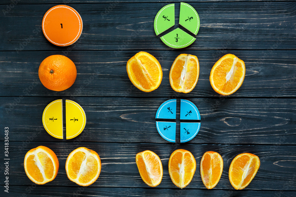 Сolorful math fractions and oranges as a sample on dark wooden ...