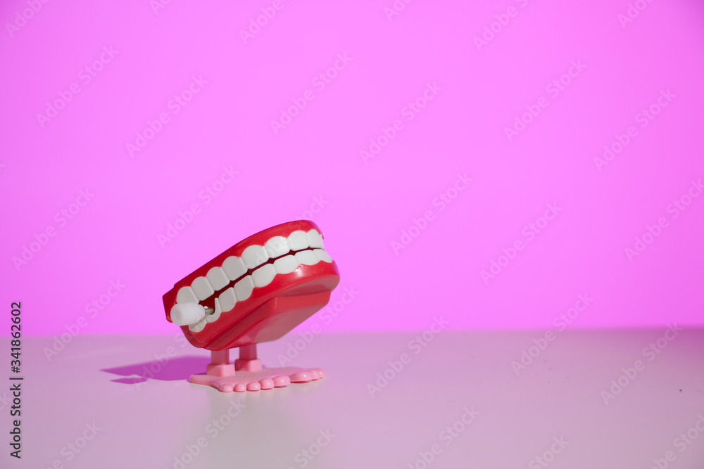 Classic chattering teeth wind-up toy on a modern pink background with ...