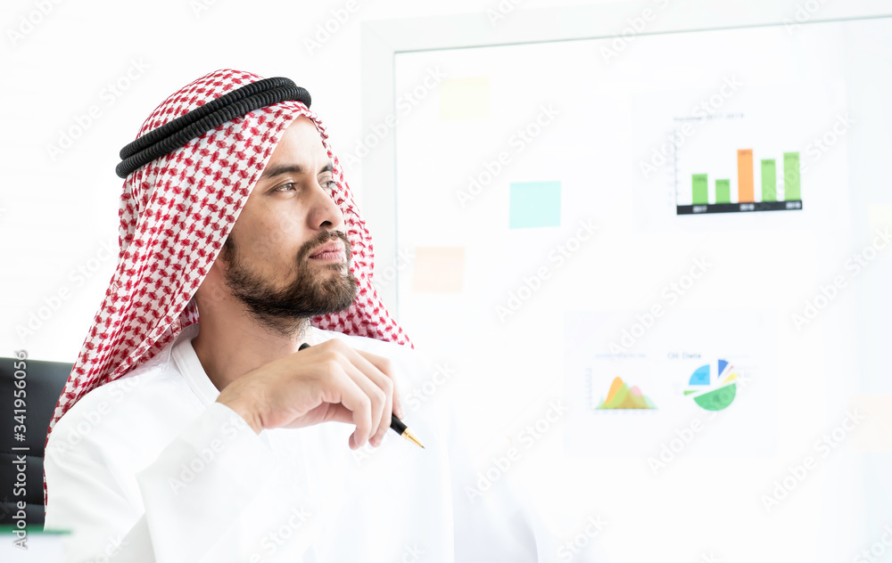 Portrait of Iranian in traditional muslim clothing sitting at workplace ...