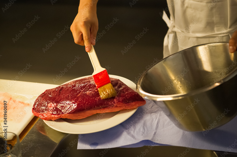 Preparing a big piece of meat to be roasted. Buttering and marinating a ...