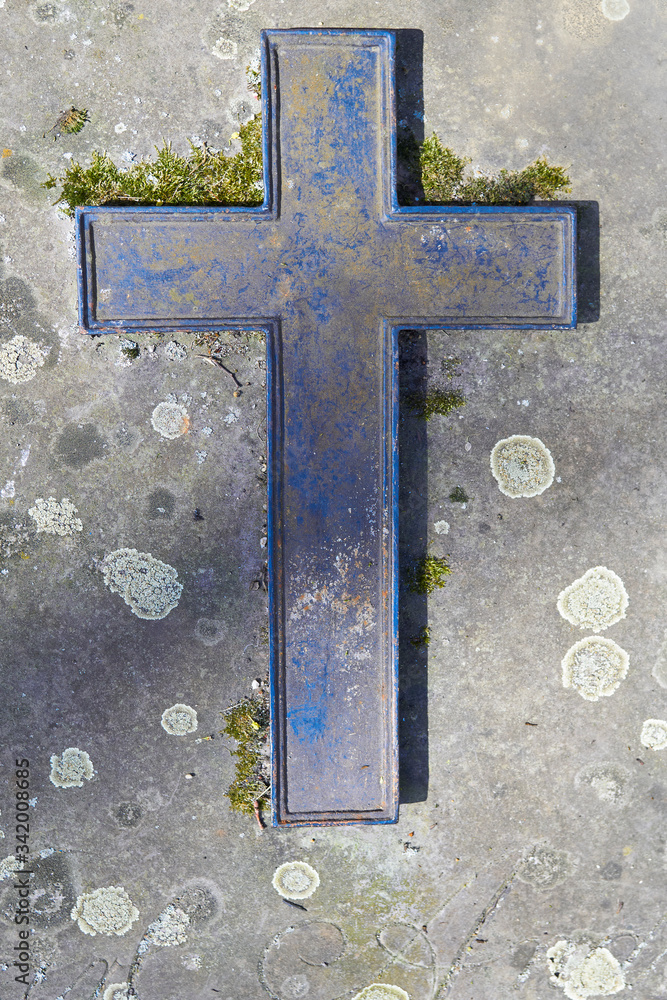 Simple blue painted iron christian cross decorating an ancient anonymus ...