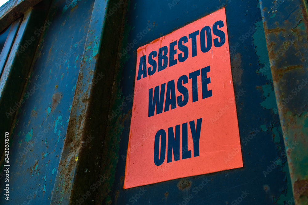 Asbestos Waste Only warning sign on a dark rusty old construction ...