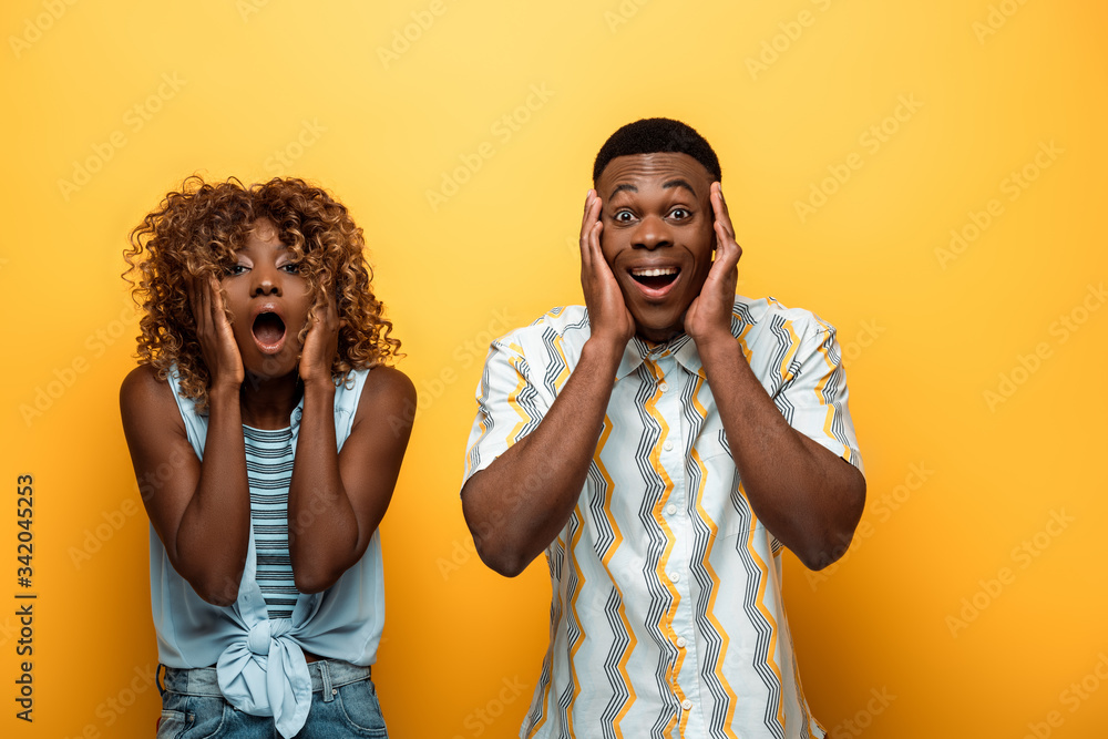 shocked african american couple with open mouths touching faces on ...