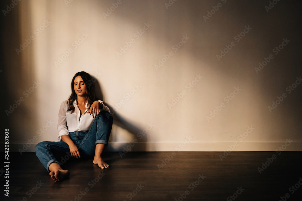 Gorgeous barefoot brunette in white shirt and blue jeans smiling with ...