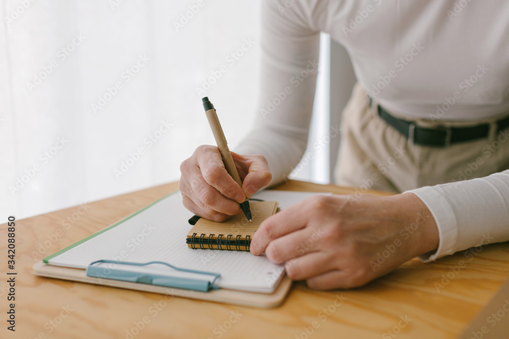Faceless casual businesswoman bending on wooden table and writing in ...
