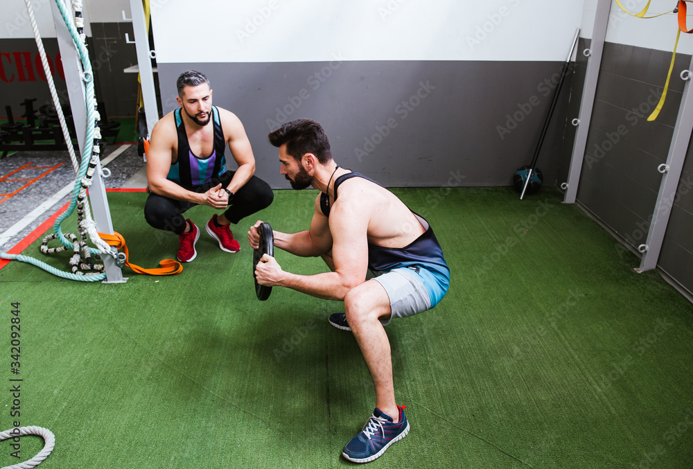 High angle side view of focused strong sportsman doing squat exercise ...